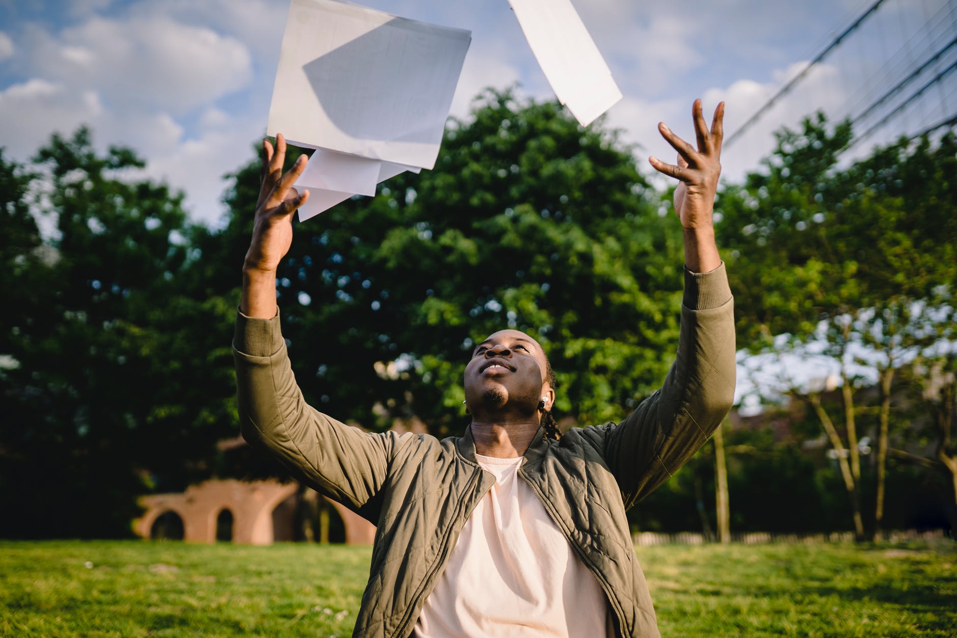 african american man throwing paper sheets up in park – Katharina Steiner